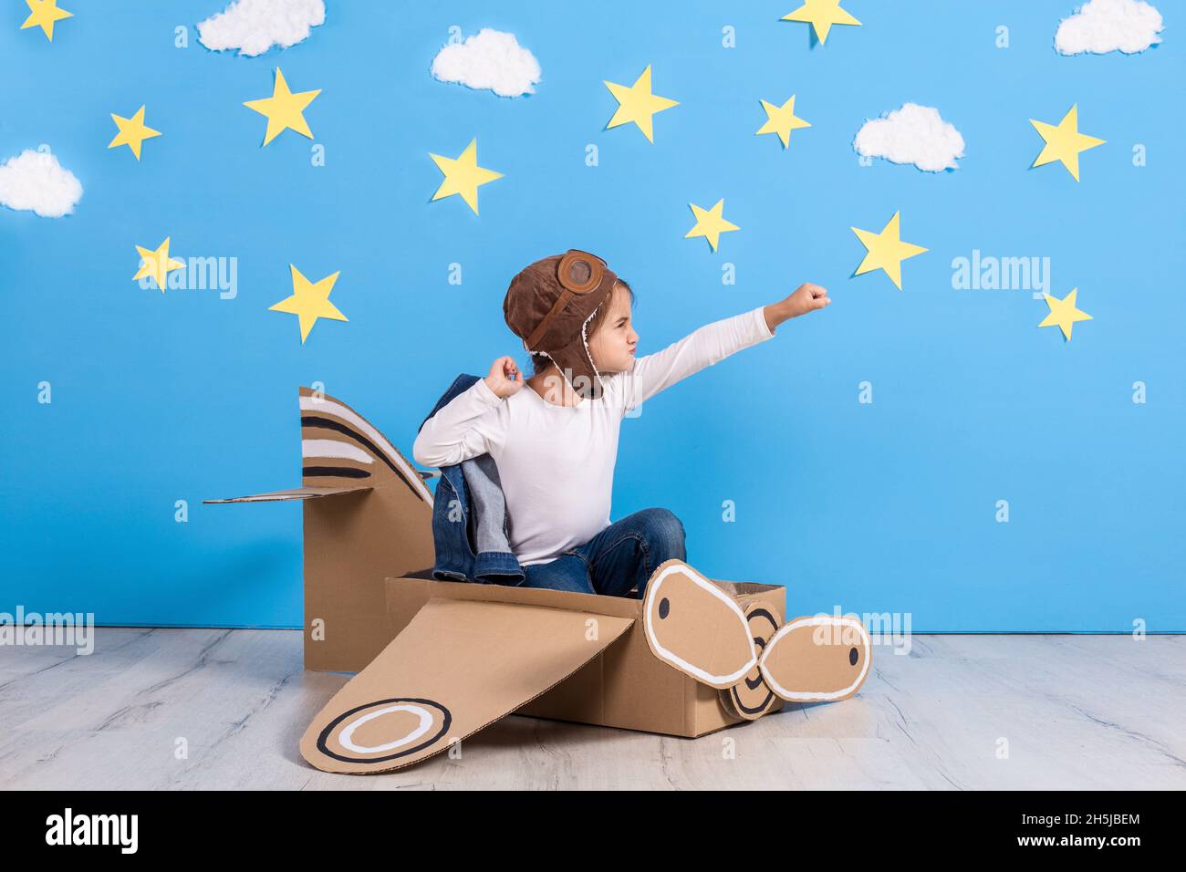 Little child girl in a pilot's costume is playing and dreaming of ...