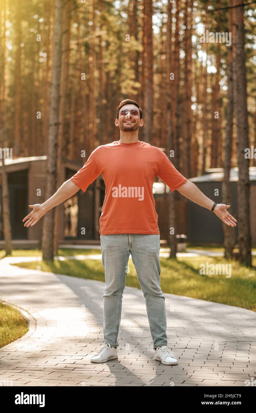Confident smiling man standing under sun in park Stock Photo - Alamy