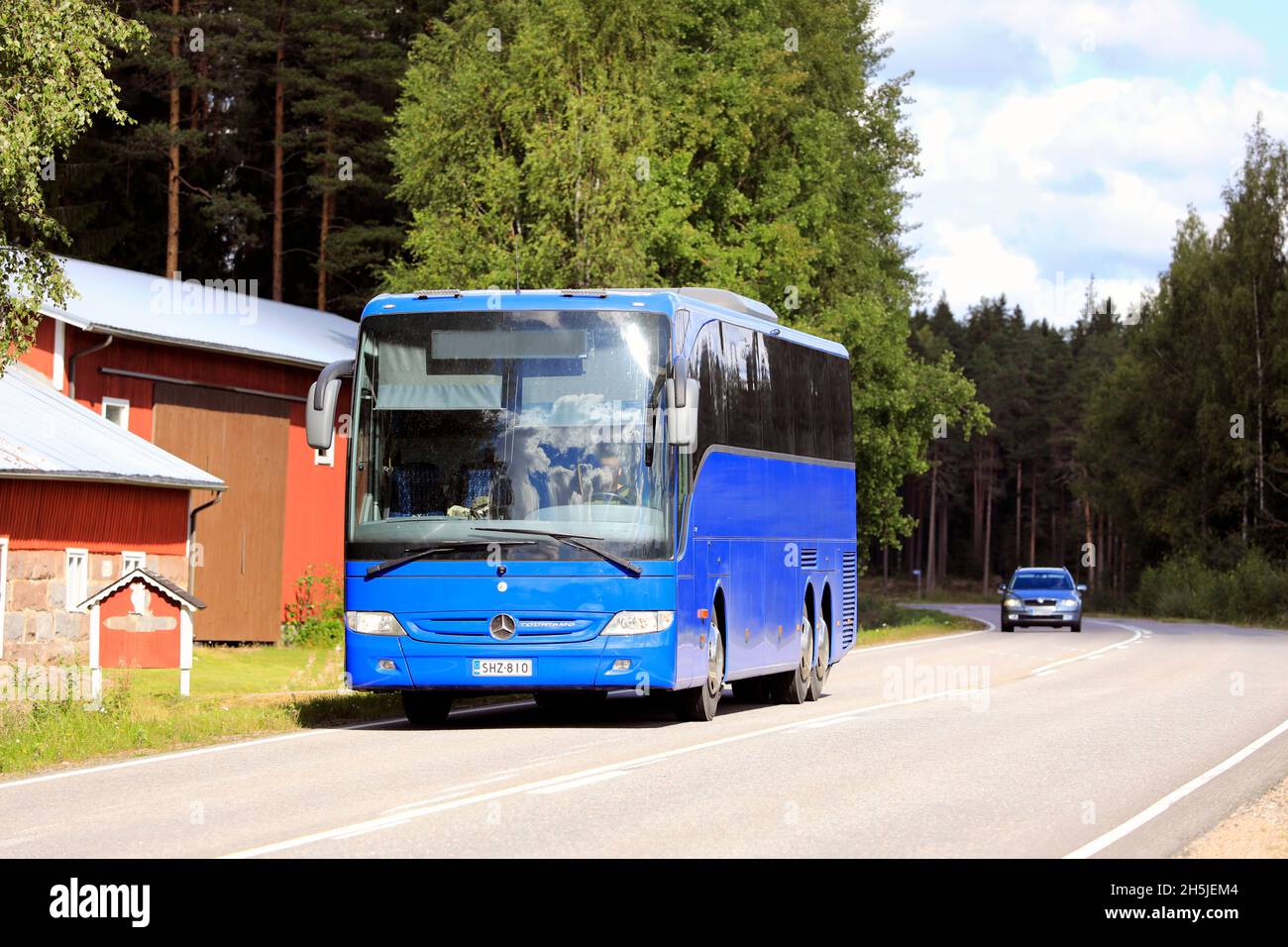 Blue Mercedes-Benz Tourismo Coach Bus travels along rural road on a ...