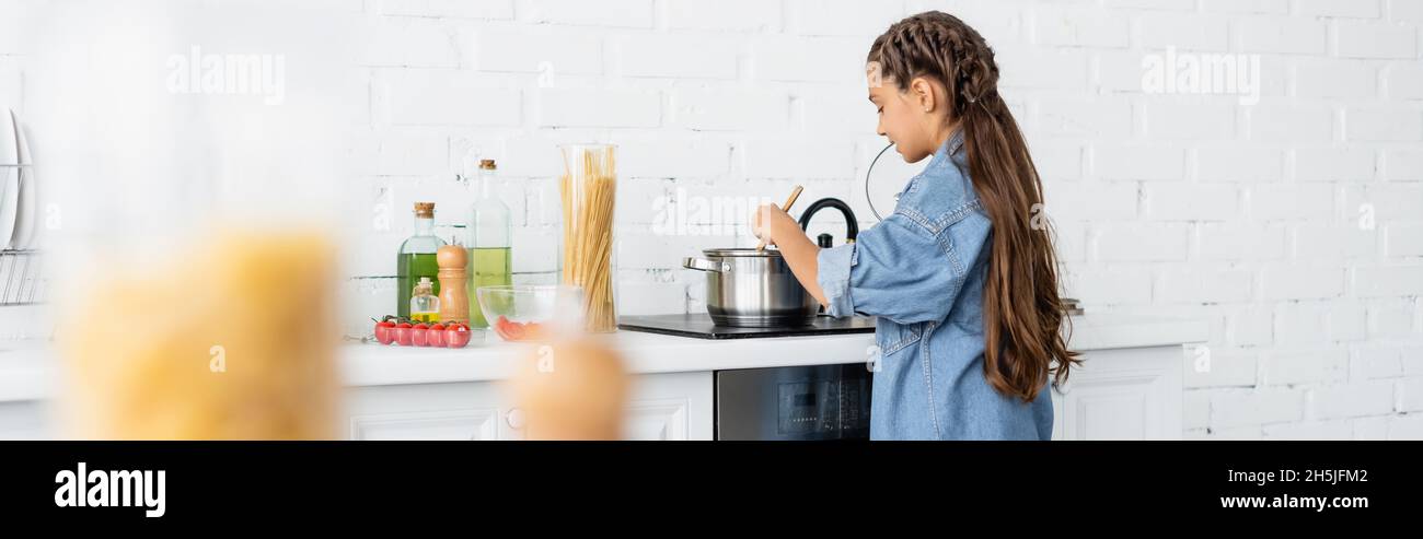 Child cooking near saucepan on stove and ingredients in kitchen, banner ...