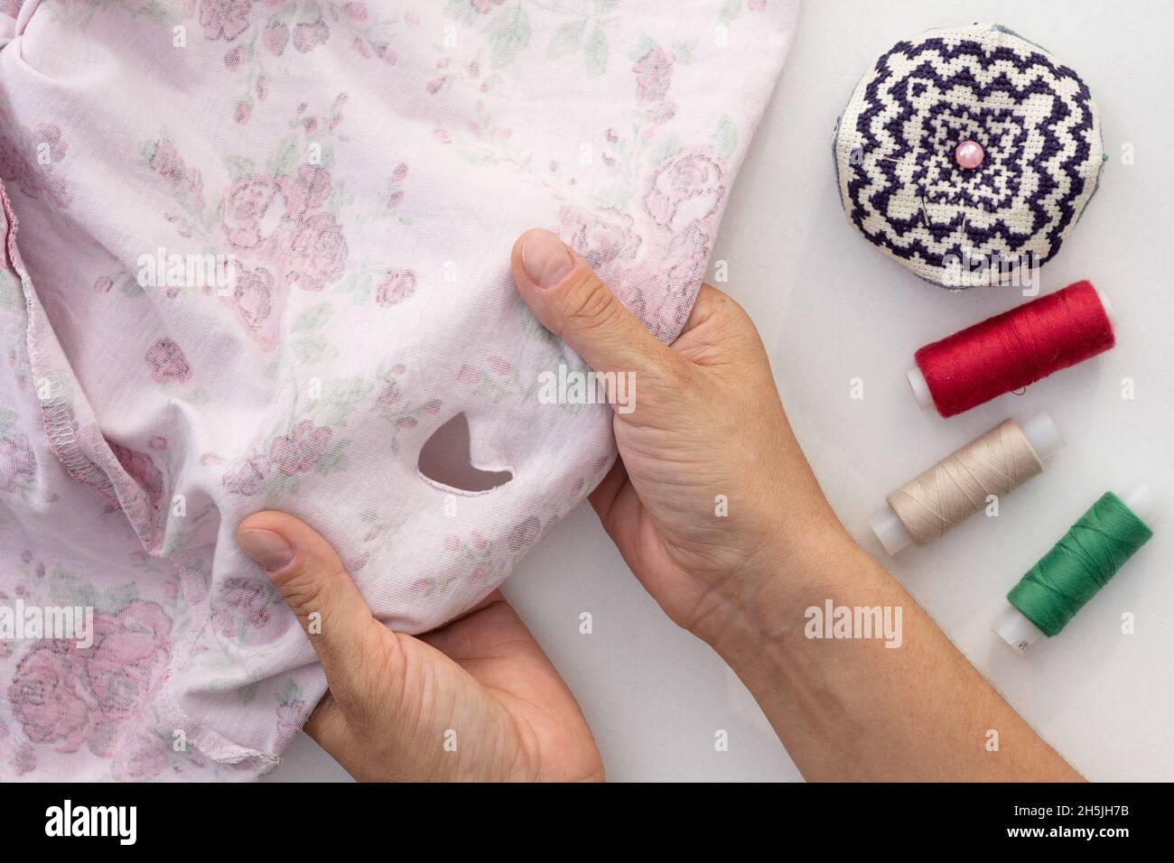 Woman hand holding torn cloth seamy side showing hole on white ...