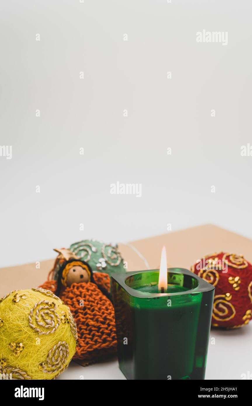 green scented candle in a glass with Christmas time decorations on a ...