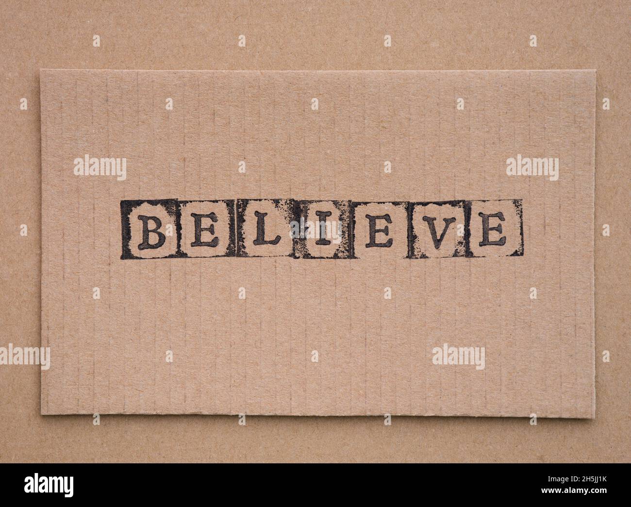 Cardboard with word Believe made by black alphabet stamps Stock Photo ...