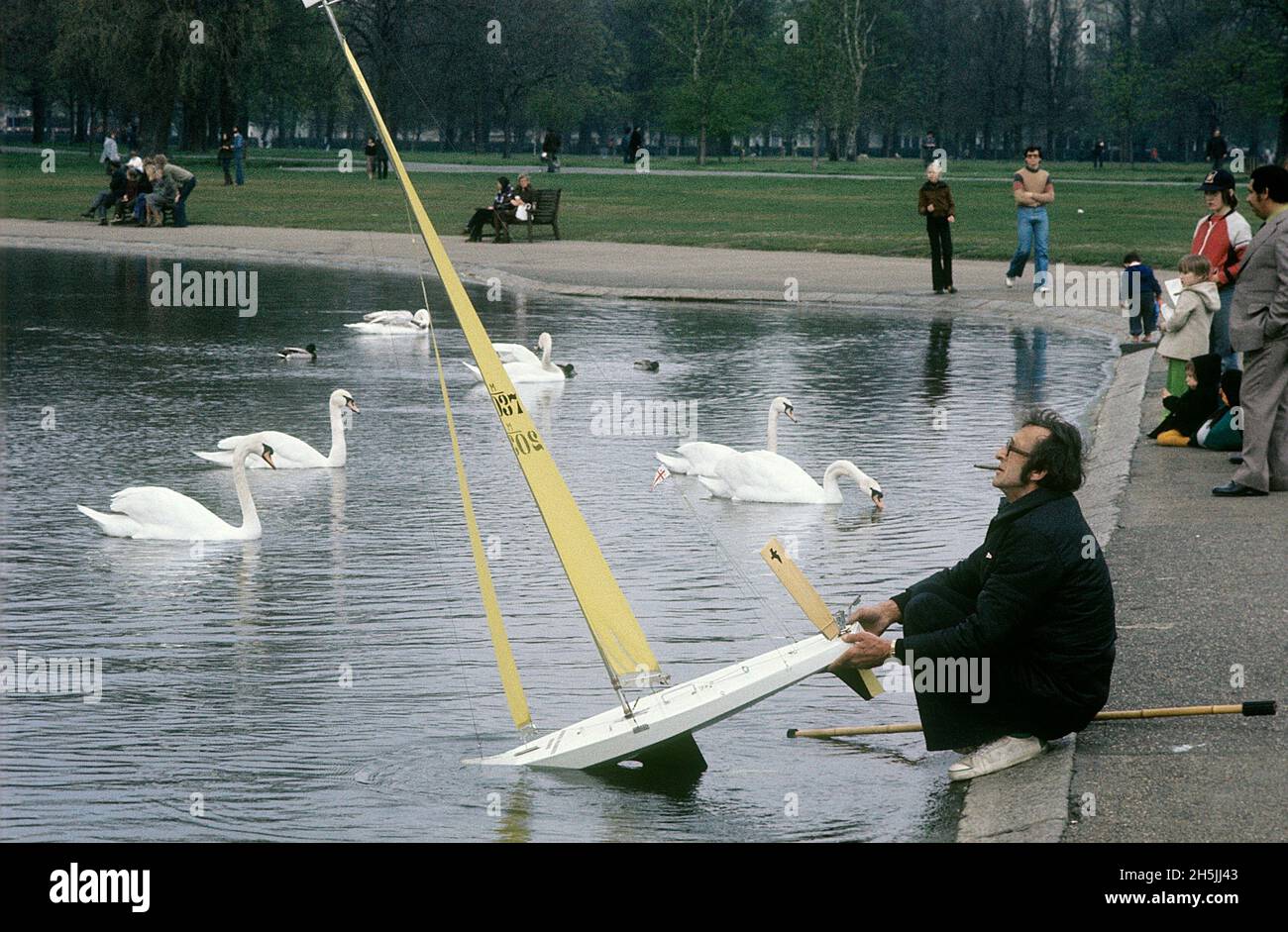 London 1982. A London park and a man launching his model sailing boat ...