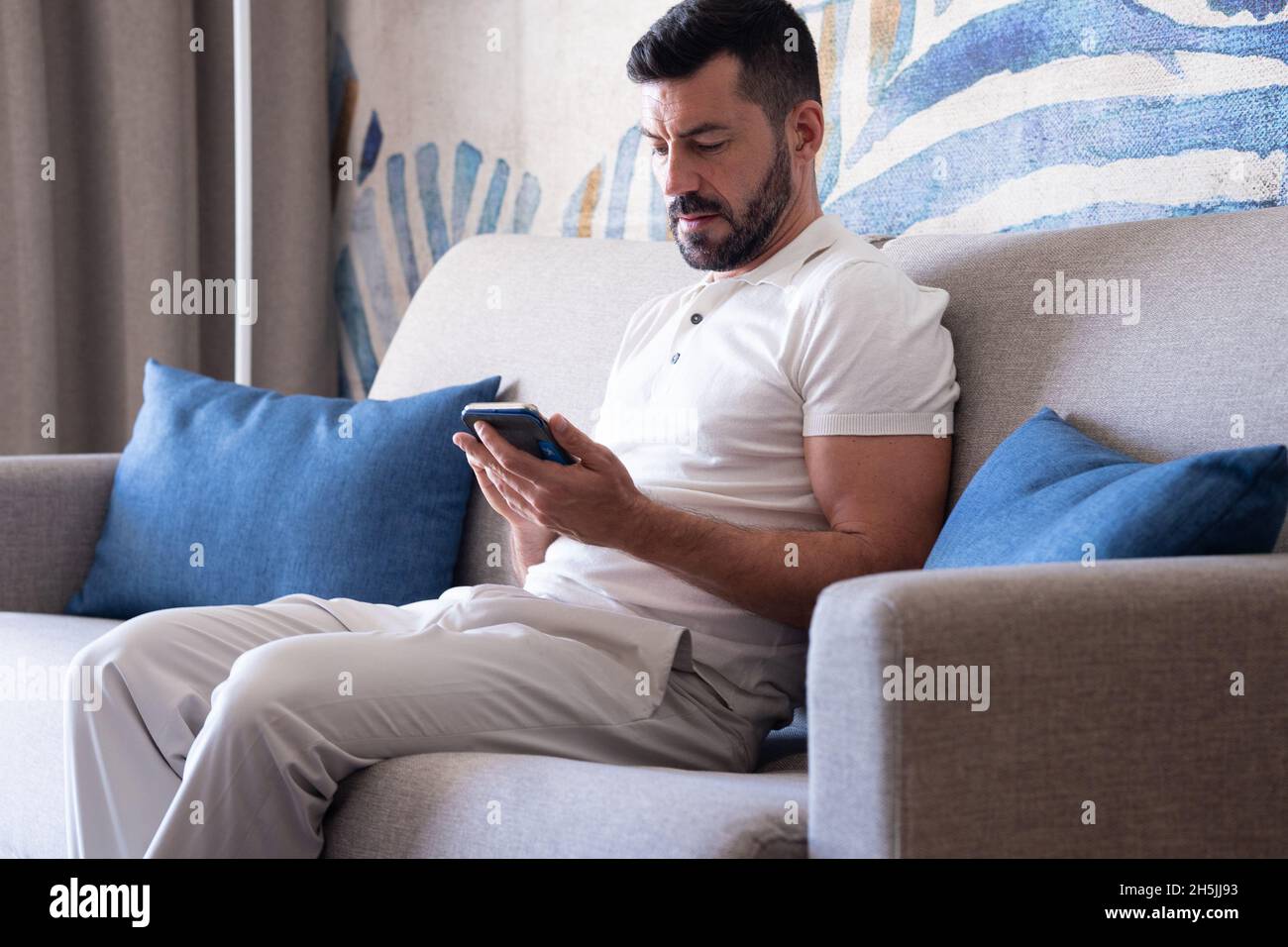 man sitting on the sofa in the hotel room interacting with the mobile ...