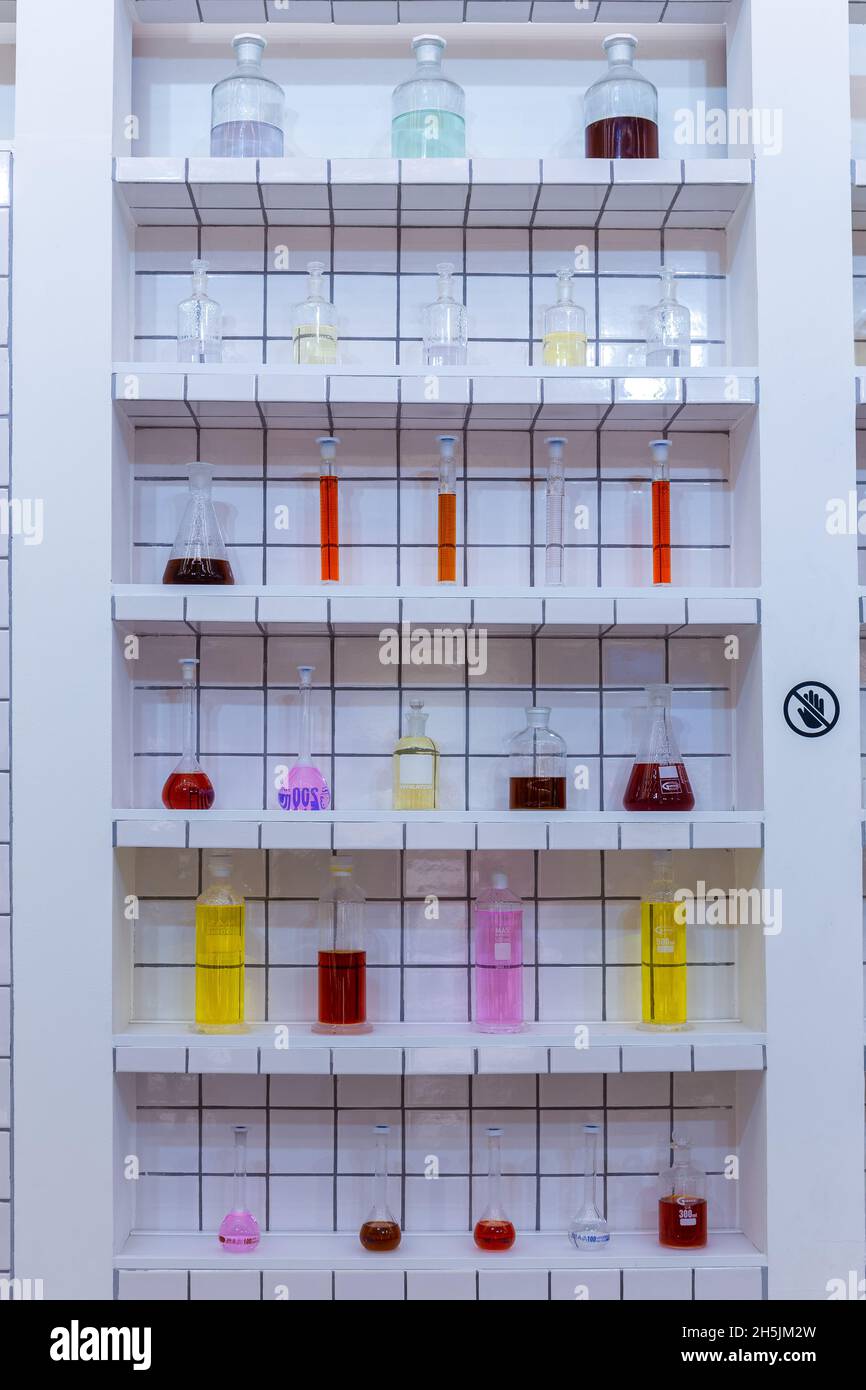 Laboratory cabinet with colorful vials, flasks and tubes containing ...