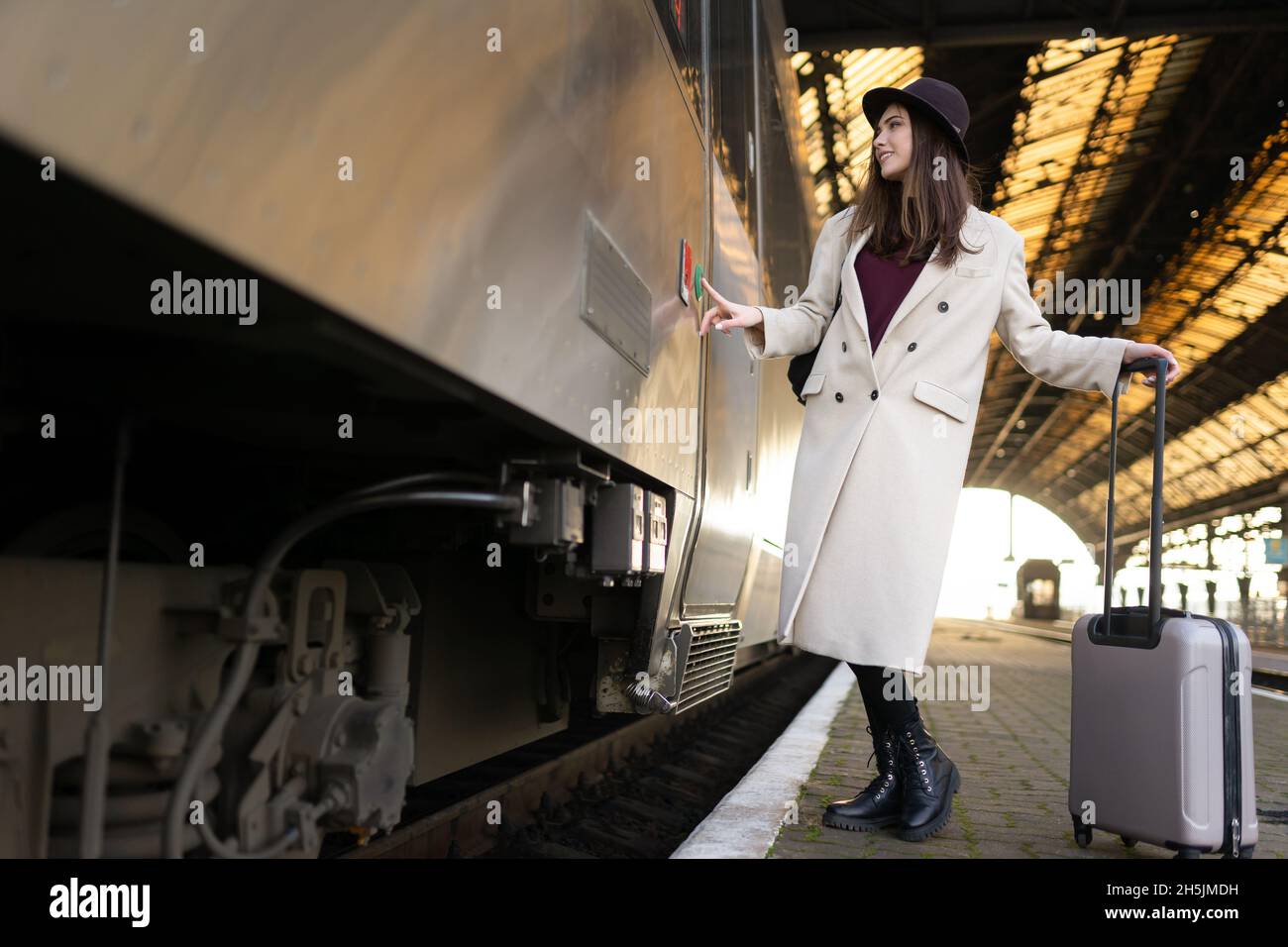 Cheerful woman presses button on the train door to enter. Railway trip ...