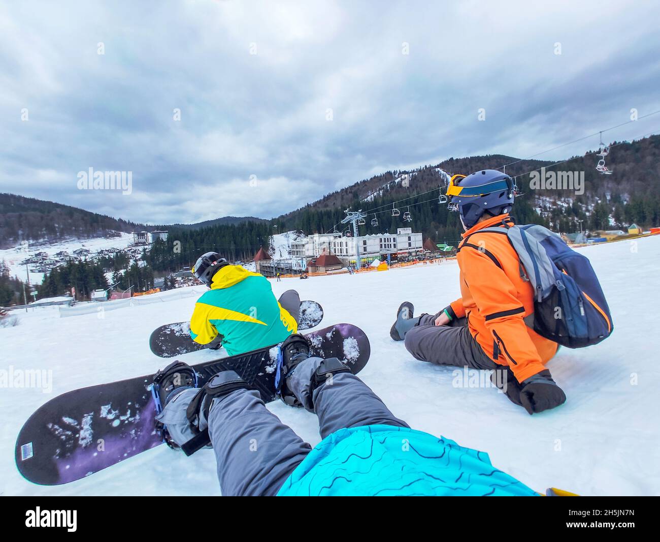 friends sitting at snowed hill with snowboard. winter activities ...