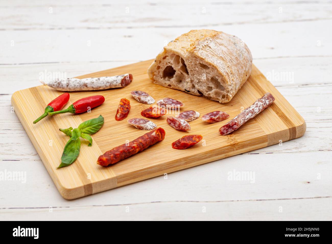 Closeup shot of a bread, red chili peppers, and salami on a wooden ...