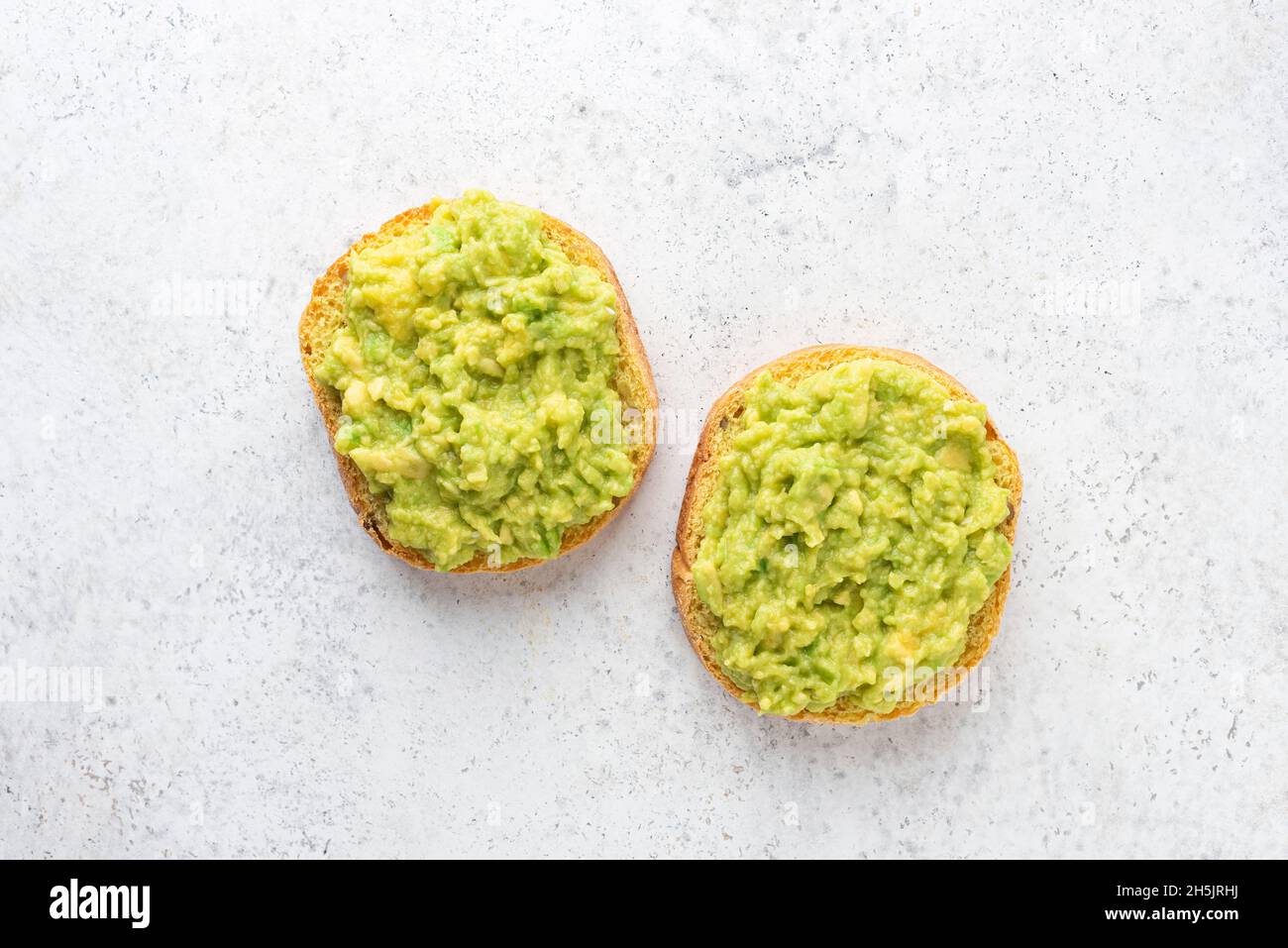 Mashed avocado on a round bun cut in halves. Healthy vegan avocado ...