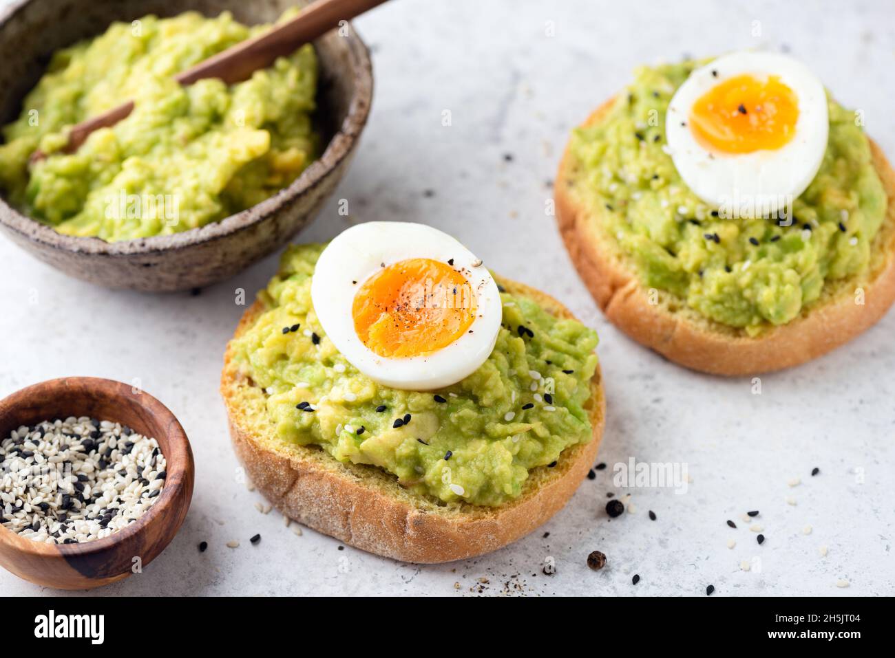 Mashed avocado and boiled egg on toasted bun bread on grey cement ...