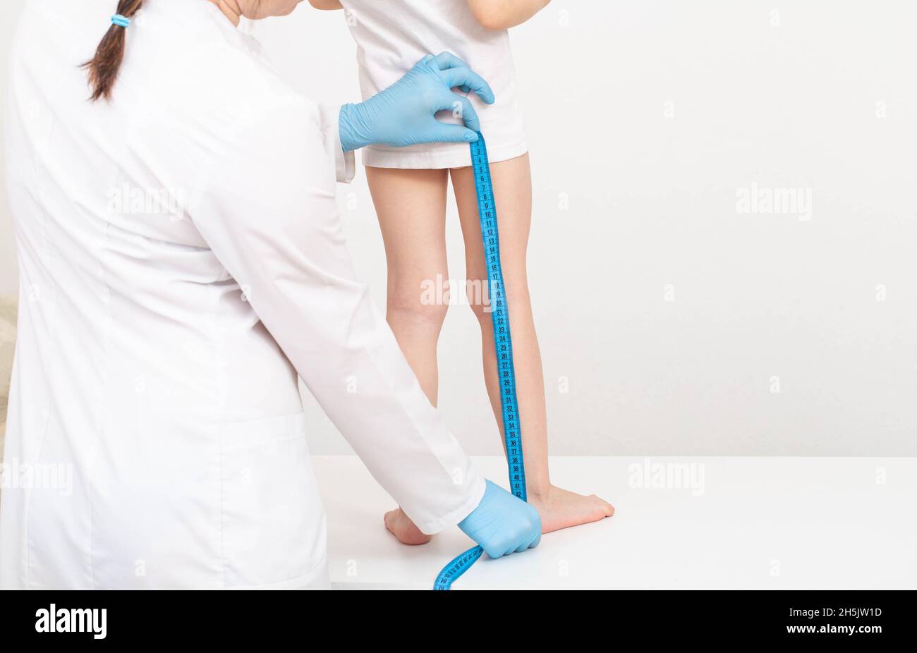 A doctor in blue gloves with a measuring tape measures the length of ...