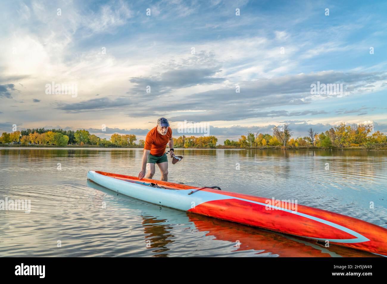 senior male stand up paddler is launching his long racing paddleboard ...