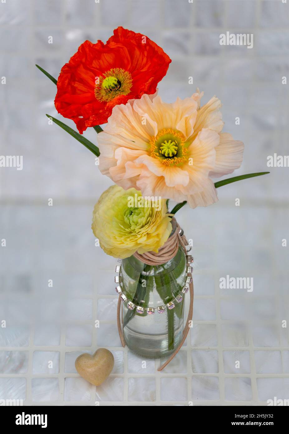 View form above of colorful poppies and ranunculus in a glass vase ...