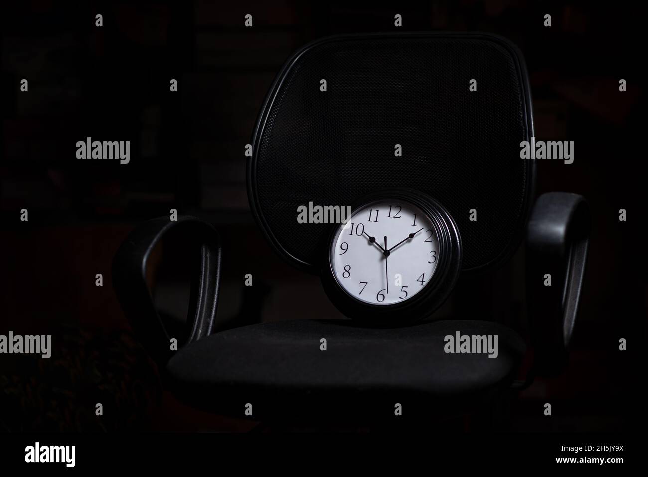 Deadline concept, time management. Clock on an office chair on a black ...