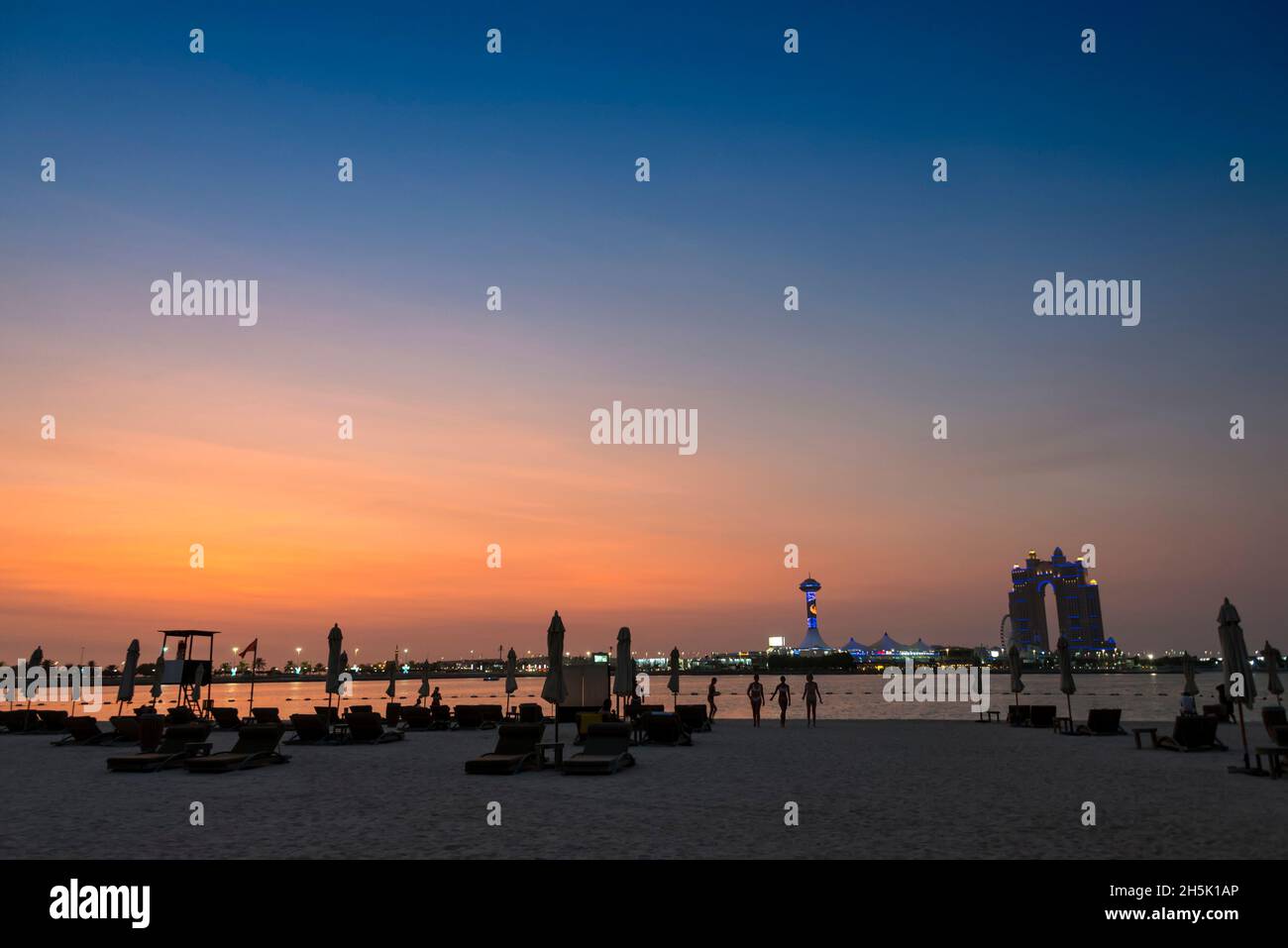 A beach club beneath the setting sun in the Persian Gulf with a view of ...