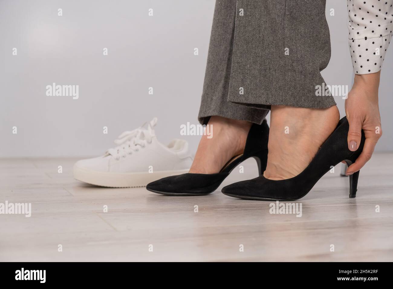 Close-up business woman takes off her shoes puts on white leather ...