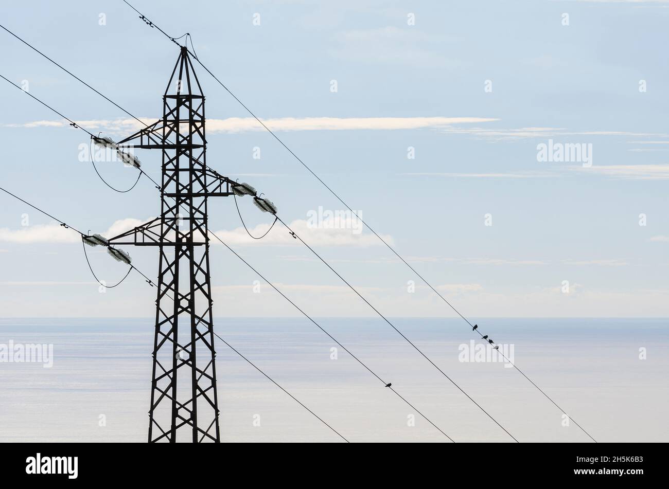 Electric pylons in front of sea and sky Stock Photo - Alamy