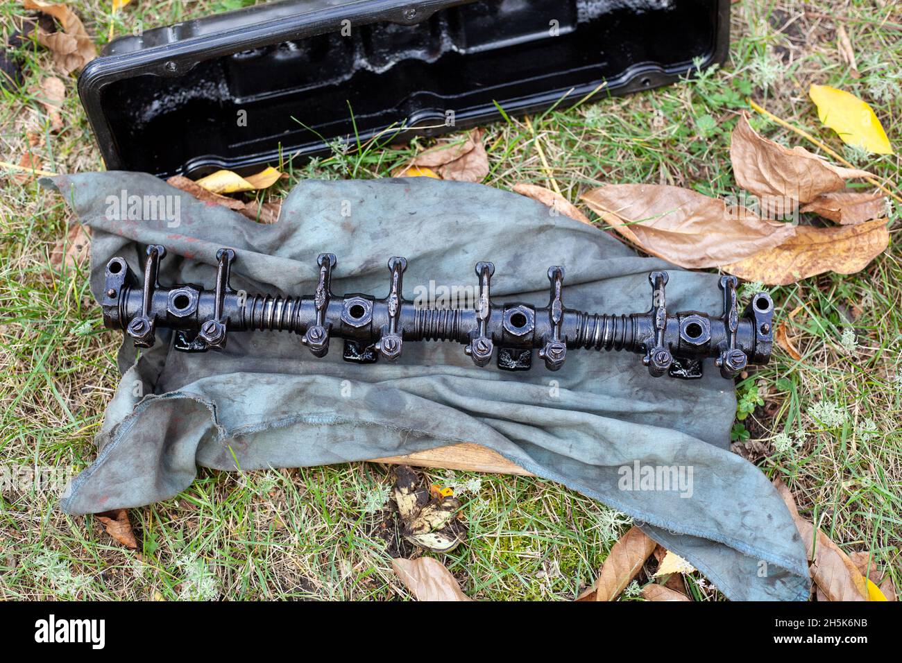 Engine part rocker shaft with rocker arms for valves lies on dirty rag ...