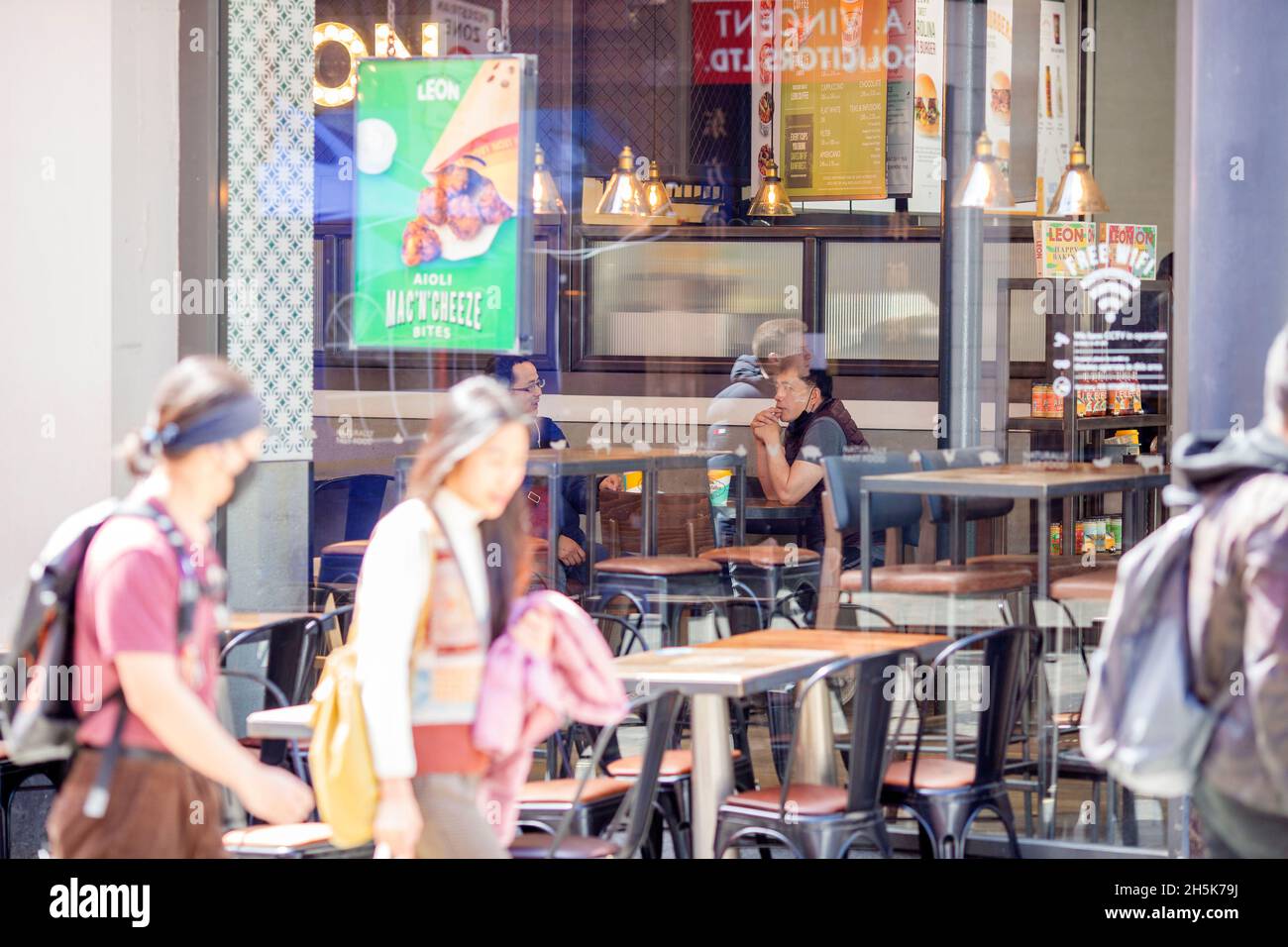 Empty seats are seen outside a restaurant where people are seen inside ...
