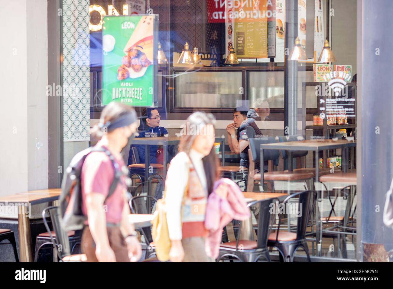 Empty seats are seen outside a restaurant where people are seen inside ...