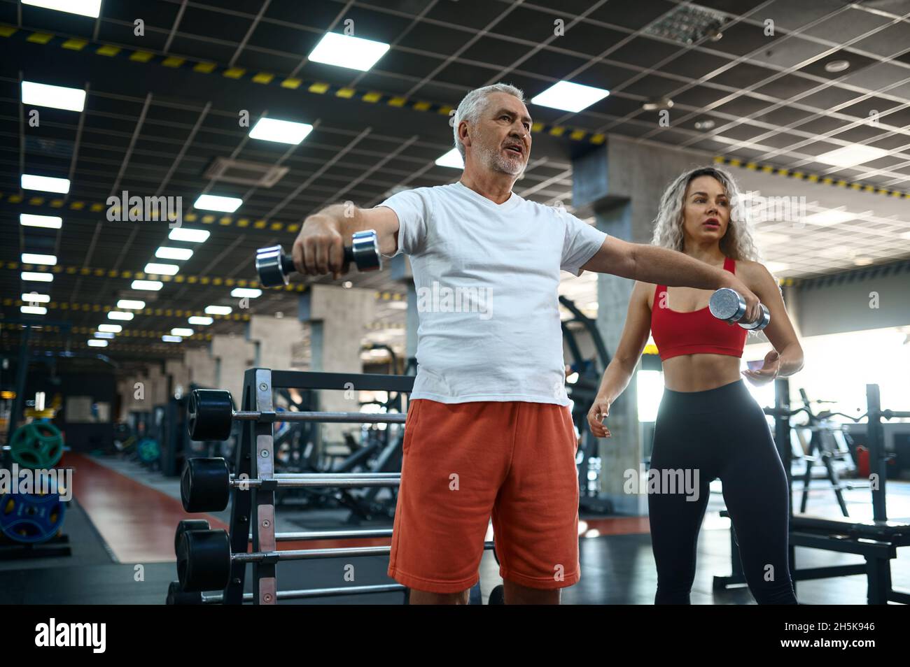 Old man, exercise with dumbbells, female trainer Stock Photo - Alamy