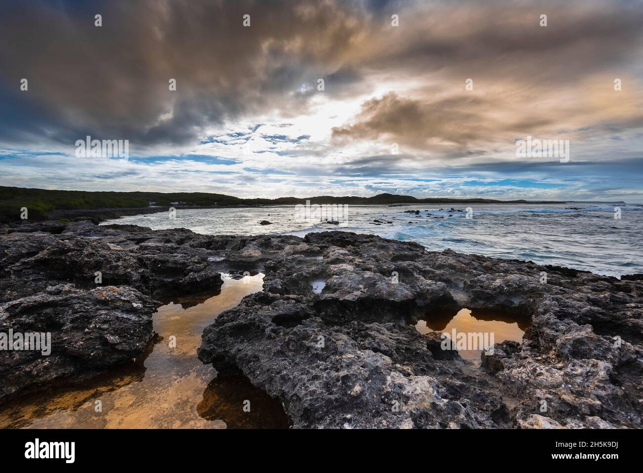 Rock formations and sunlit tidal pools along the coastal shore at ... Rock formations and sunlit tidal pools along the coastal shore at ...