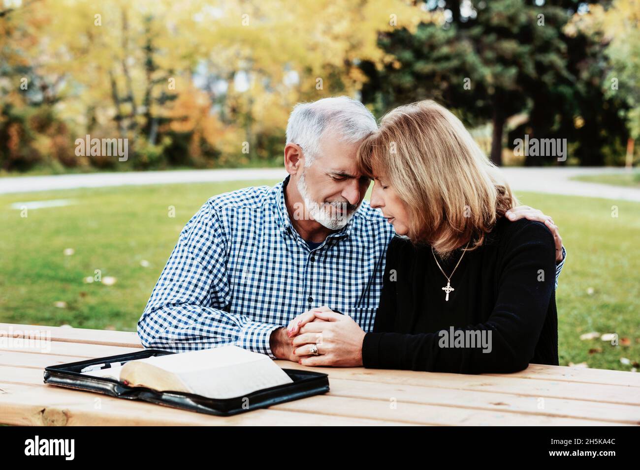 A mature couple sharing devotional time together by studying the Bible ...