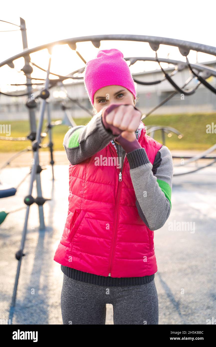 Young fit woman in fitness clothes boxing with hands in fists and makes ...