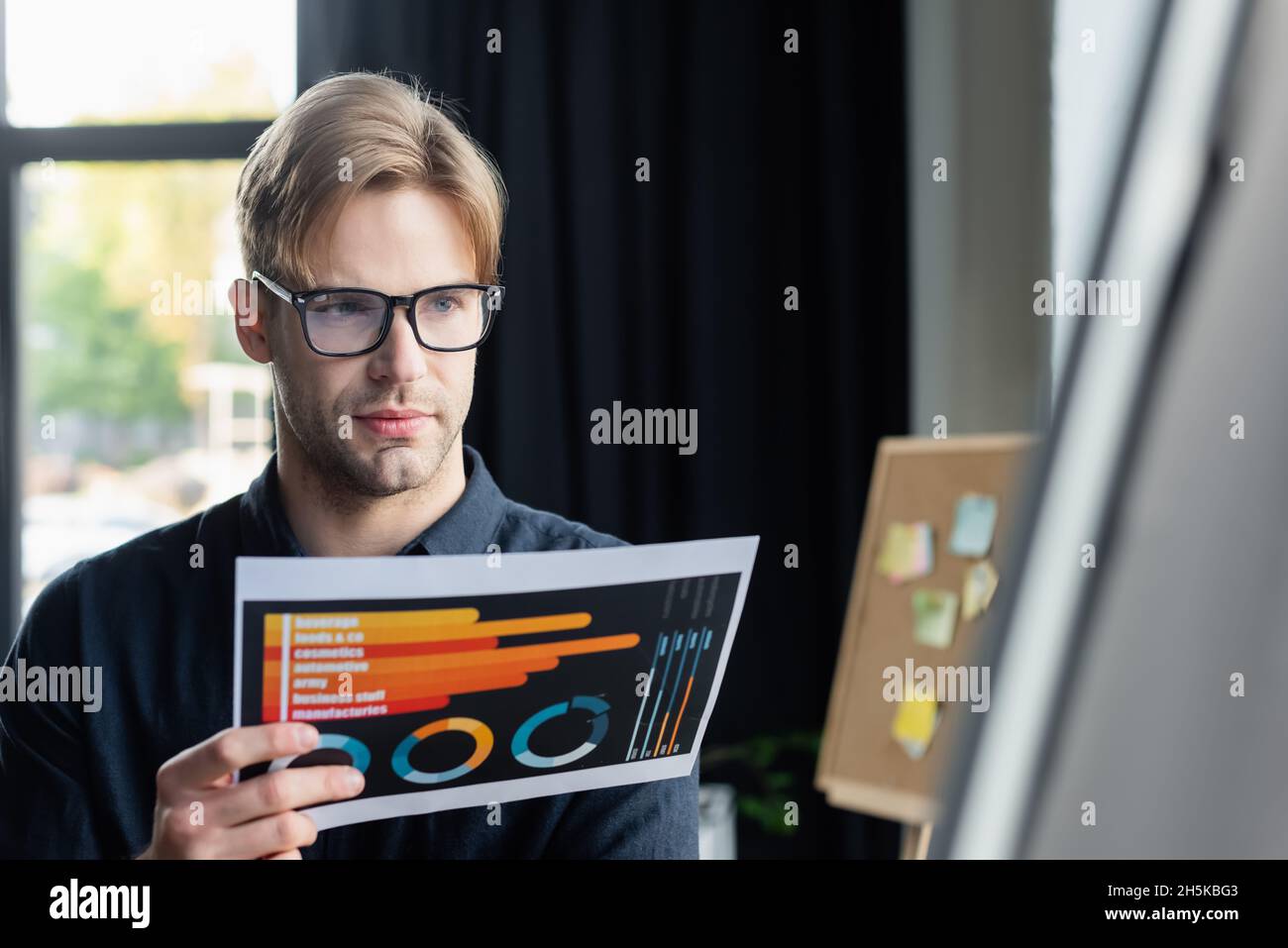 Young programmer holding document near blurred flip chart in office Stock Photo - Alamy