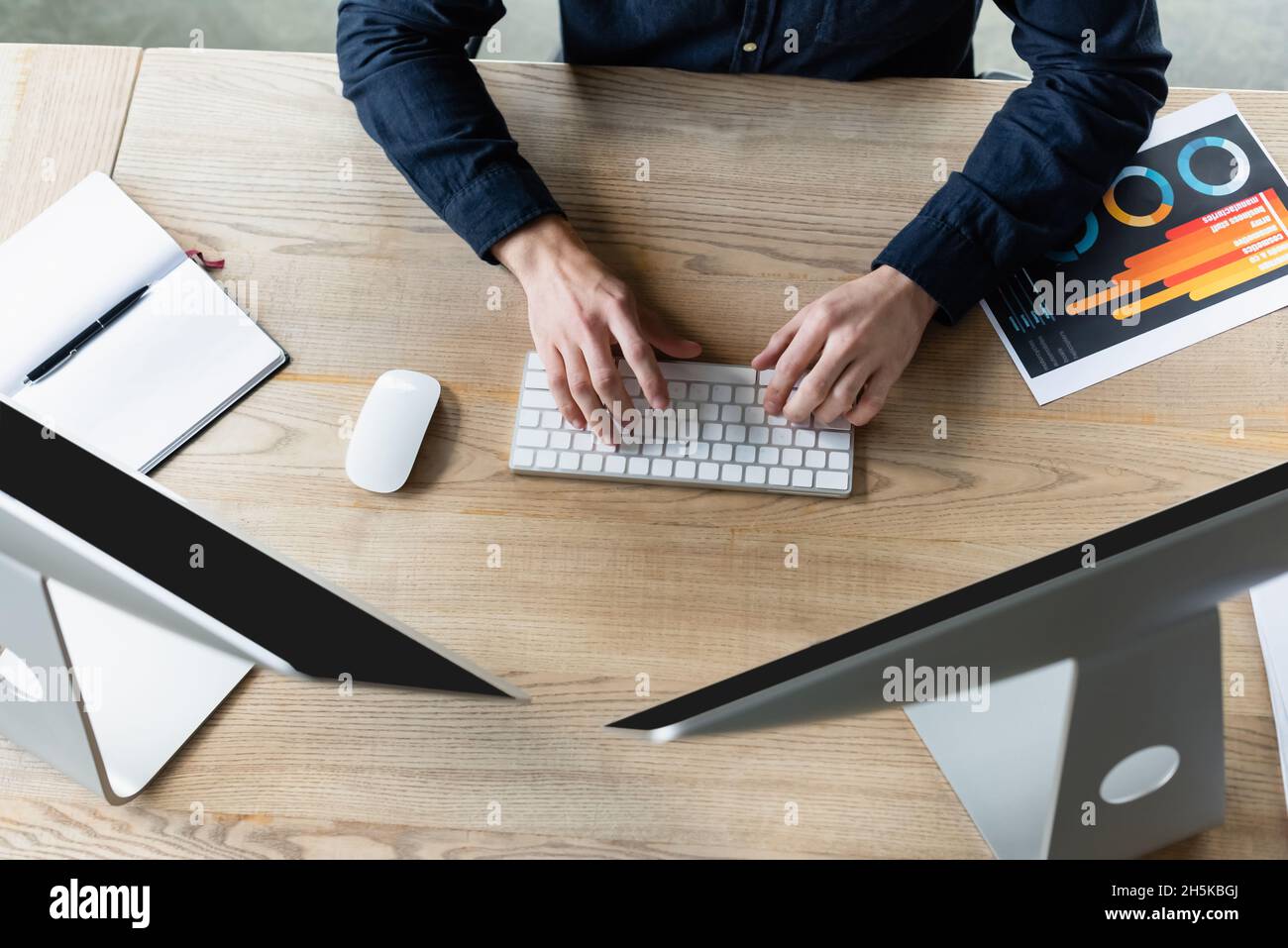 Top view of developer using keyboard near computers and notebook in ...