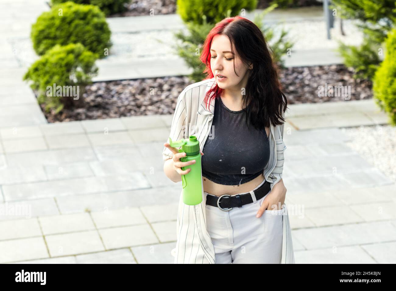 Stylish woman carry her own reusable water bottle, standing outdoors ...