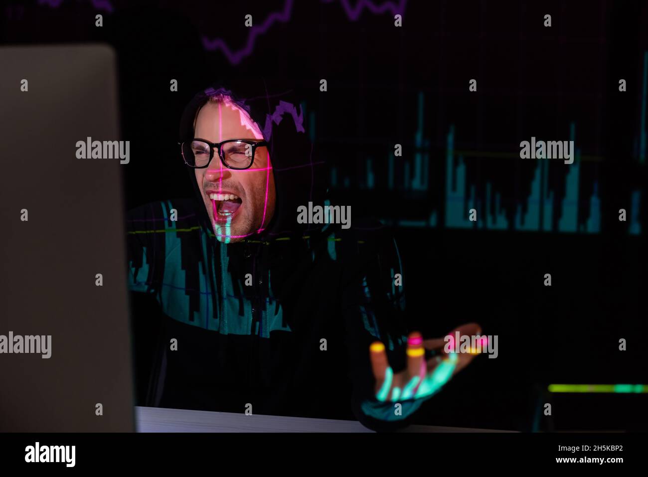 Angry hacker with charts reflection using computer on black background ...