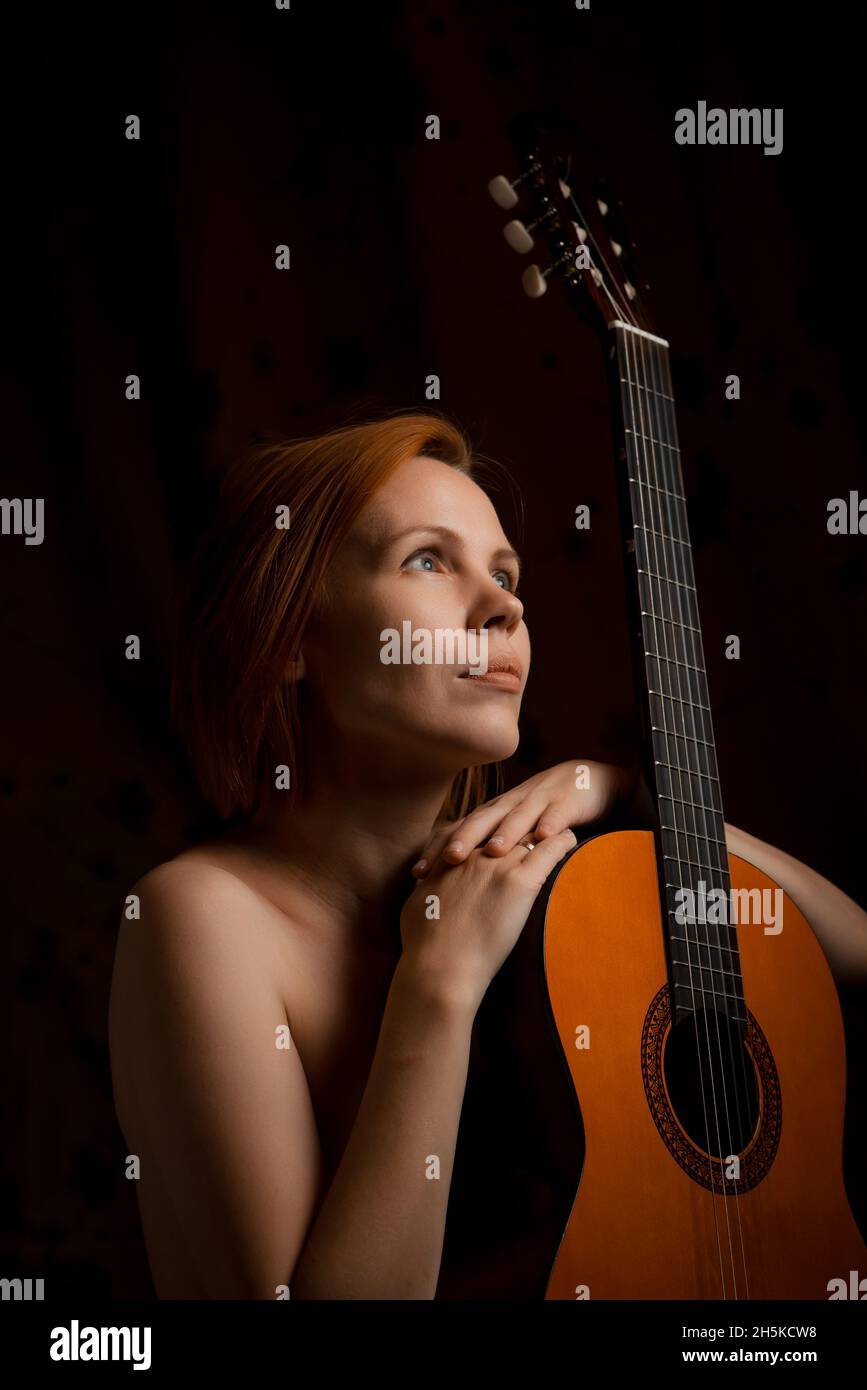Sensual attractive woman holding an acoustic guitar on a black ...