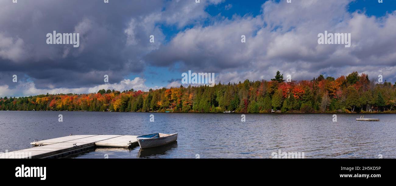 Dock on a lake with autumn coloured foliage in the forest along the ...