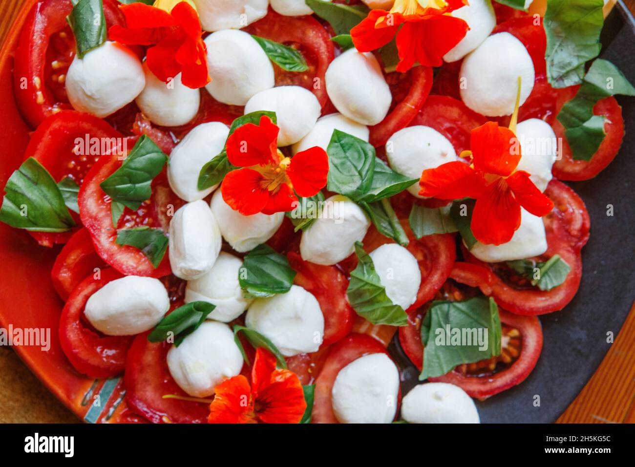 Platter of fresh tomatoes, basil, mozzarella and nasturtium flowers ...