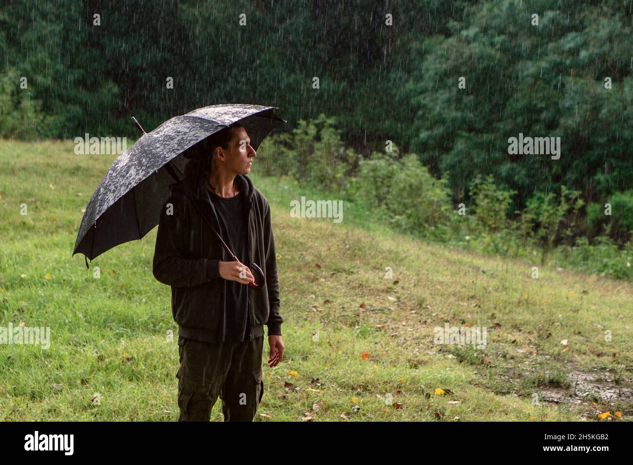 Man in the rain in green summer park Stock Photo - Alamy
