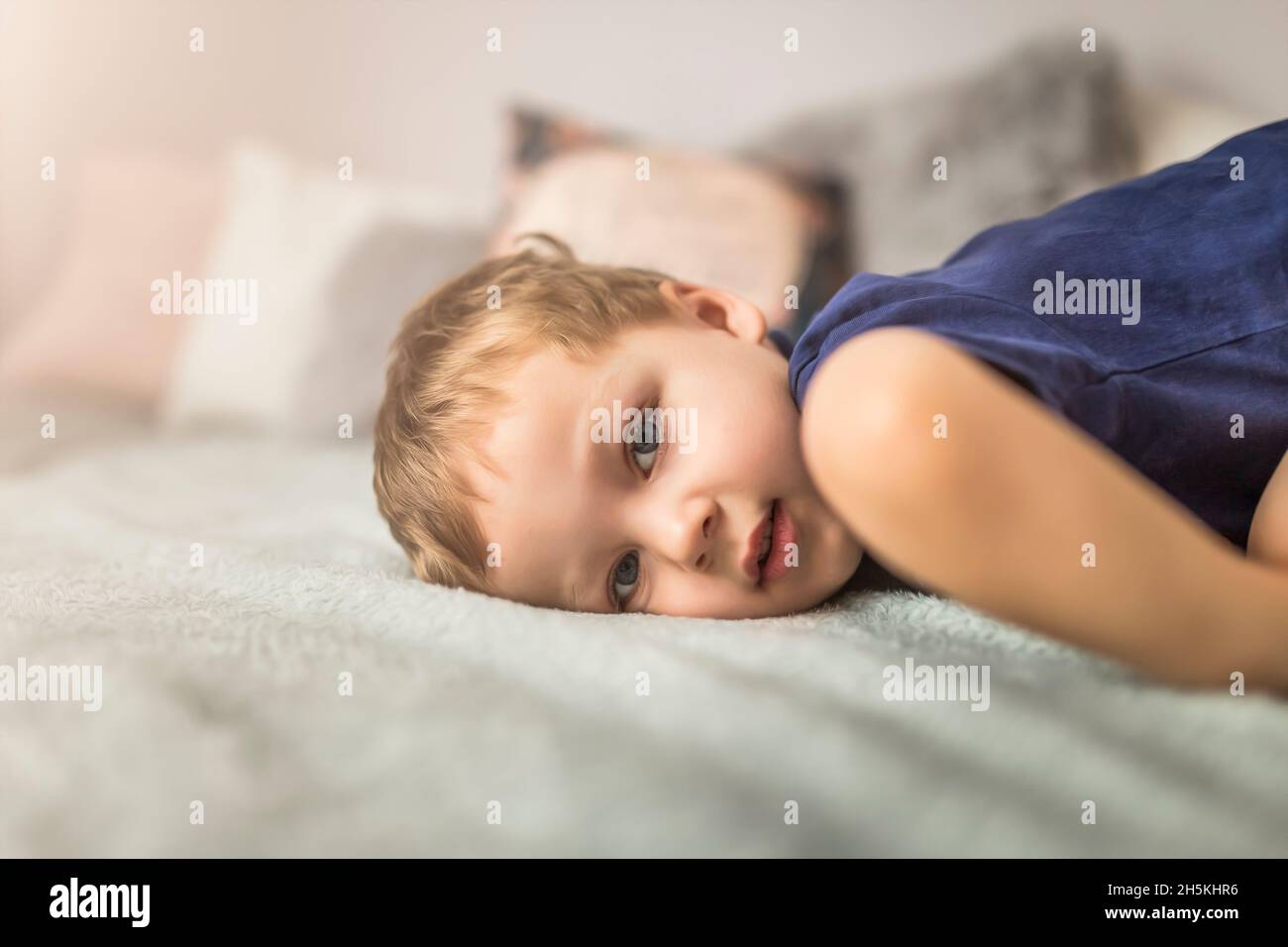 Half body of small blonde boy laying down on bed Stock Photo - Alamy