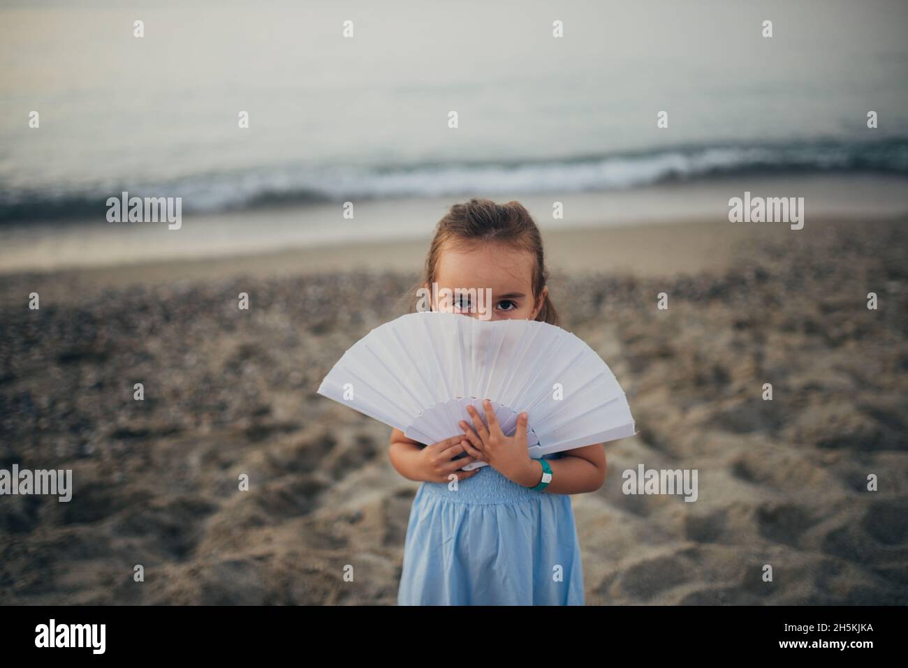 Little girl cover face with fan on the beach Stock Photo - Alamy