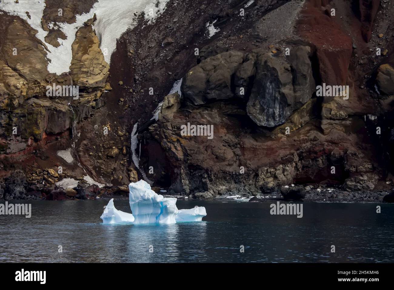 An iceberg floating past volcanic rock Stock Photo - Alamy