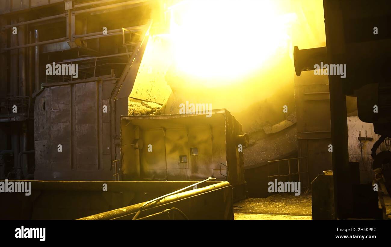 Interior view of steel mill with huge ladle of burning metal alloy ...