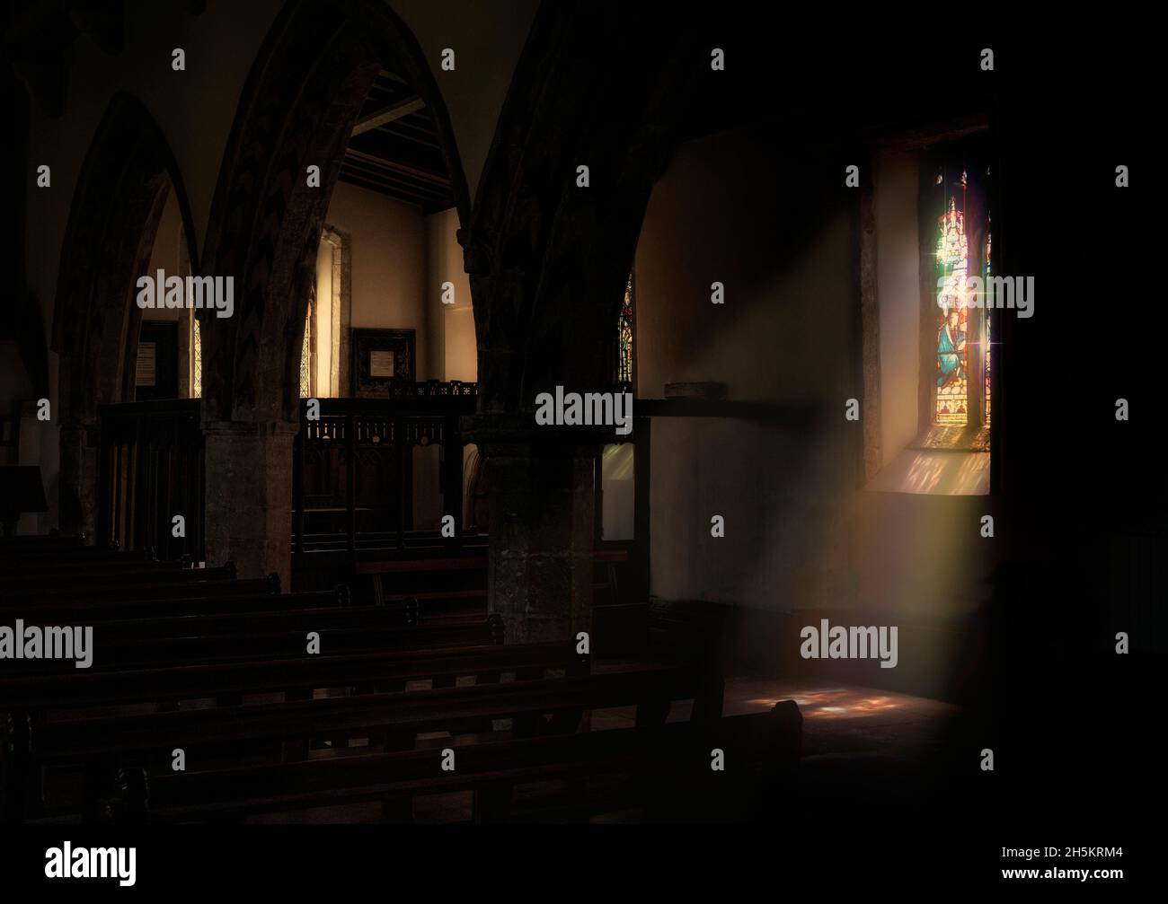 Sunlight streams through a colourful stained glass window and onto the ...