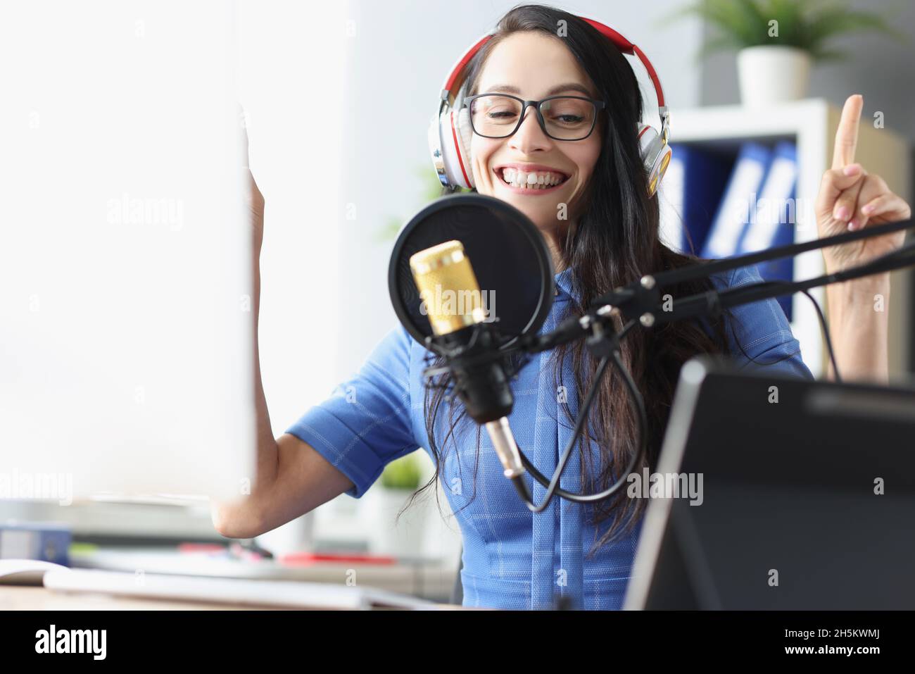 Smiling presenter woman in headphones speaking into microphone in ...