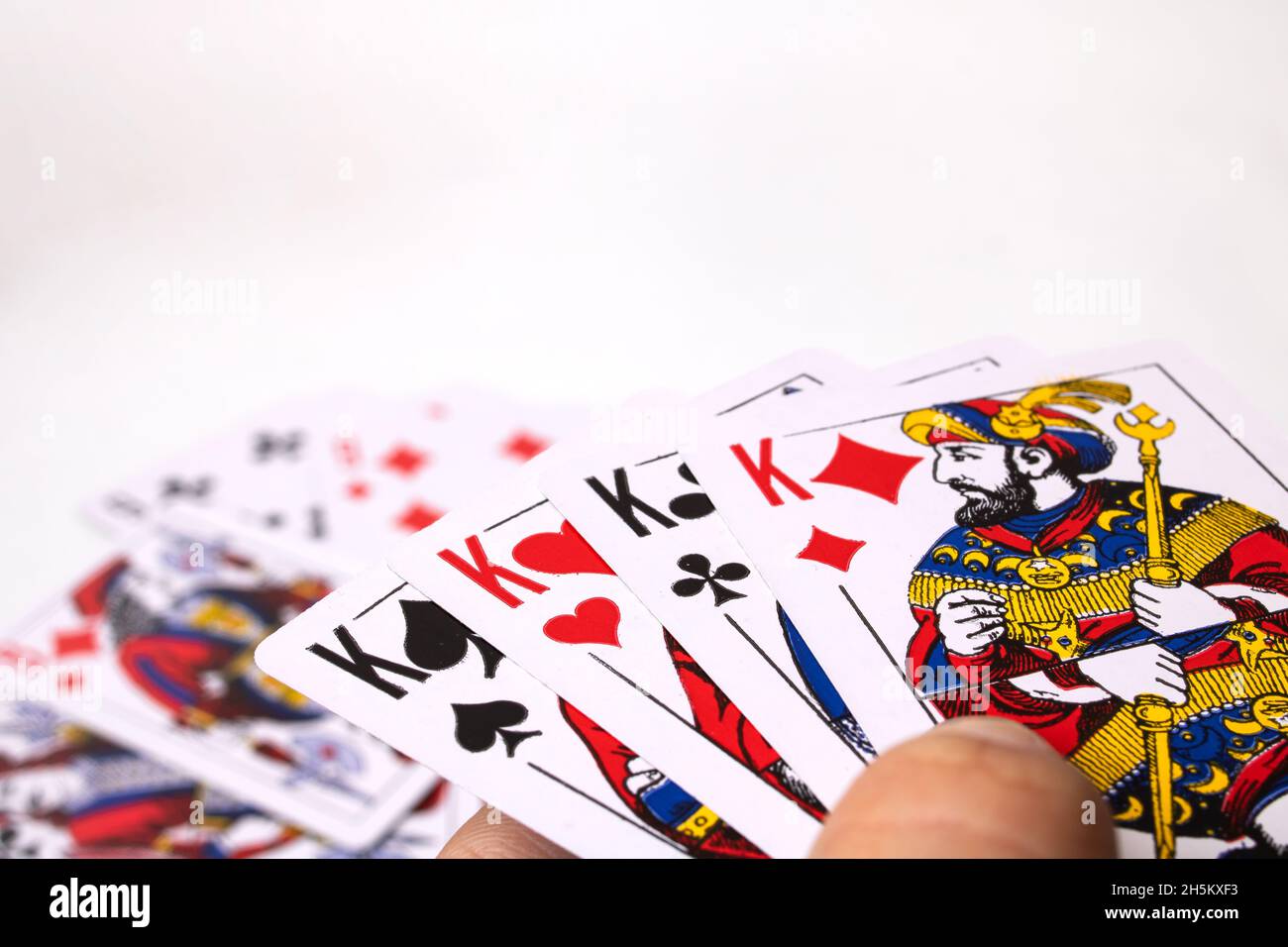 Four kings cards in hand on white background close up Stock Photo - Alamy