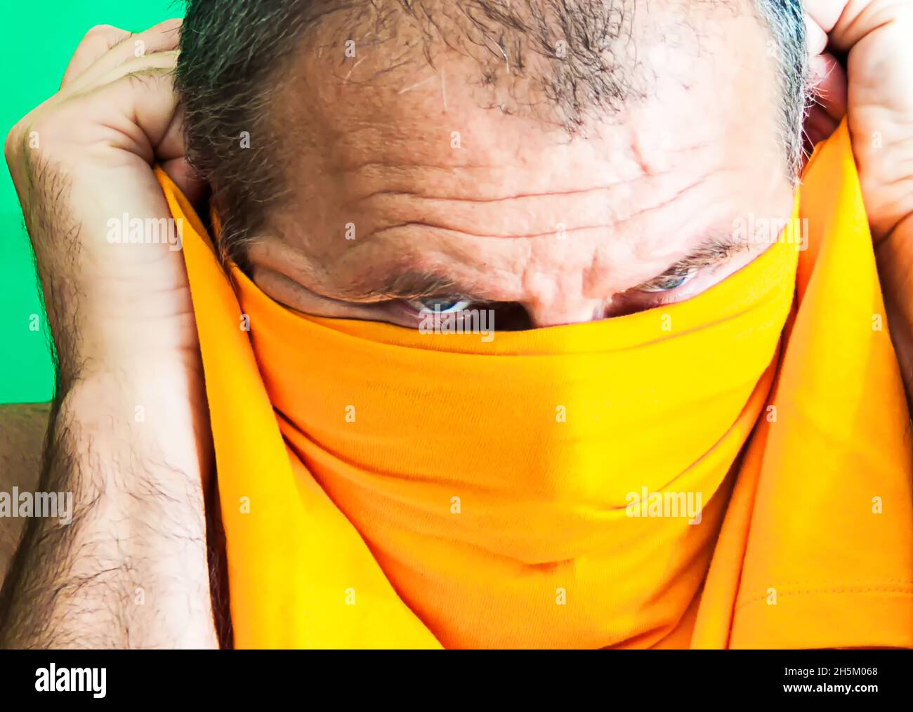 Close-up shot of a Portugal man hiding his face with a yellow T-shirt ...