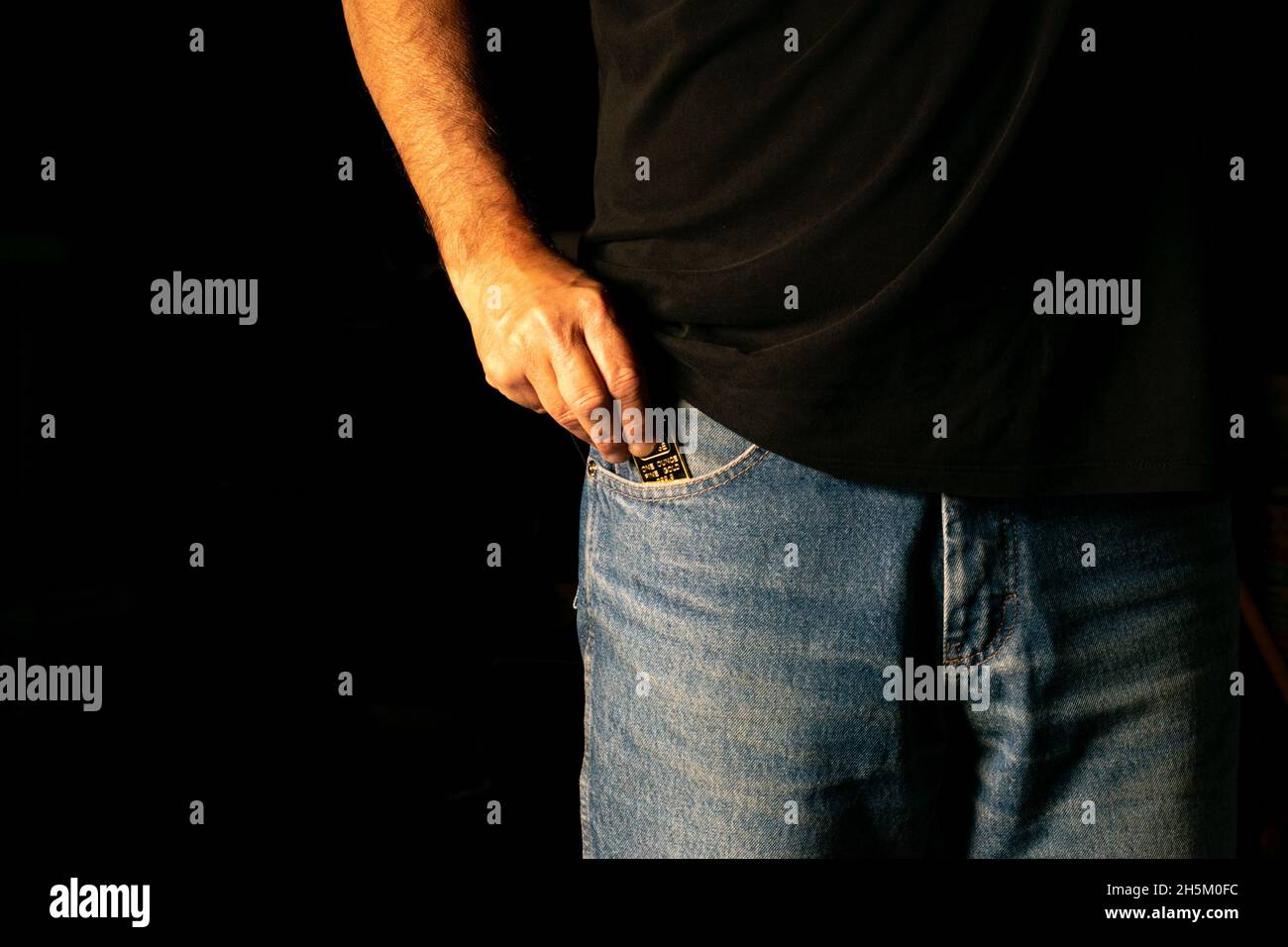 Partial view of a person keeping a small gold ingot in his pocket on a ...