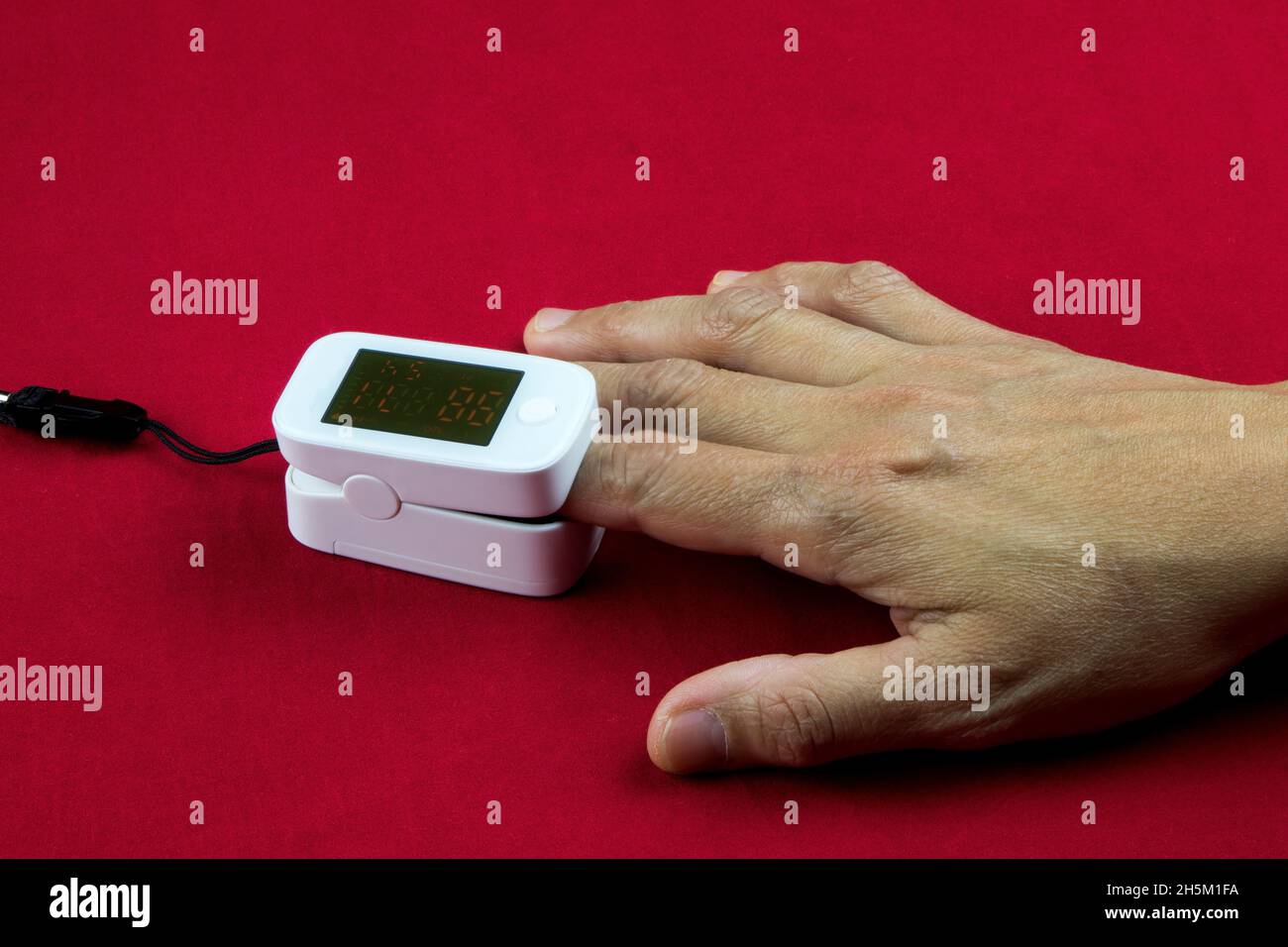 Medical oxygen level measuring meter with finger inserted on a red ...