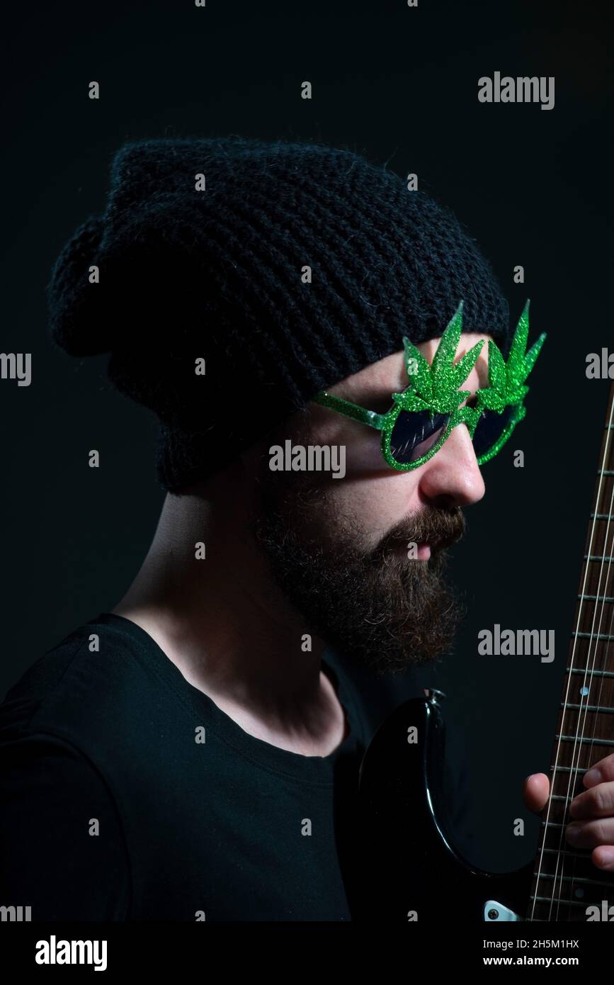 portrait of a bearded musician guy, wearing marijuana sunglasses ...