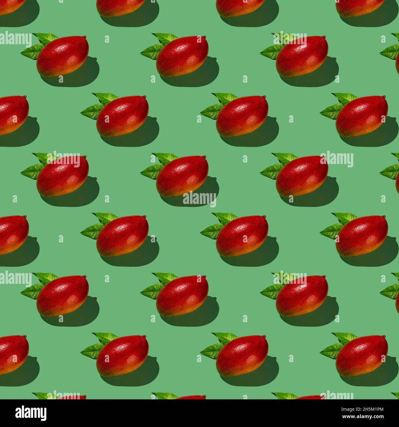 Whole ripe red Palmer mangoes cast shadow on a green background ...