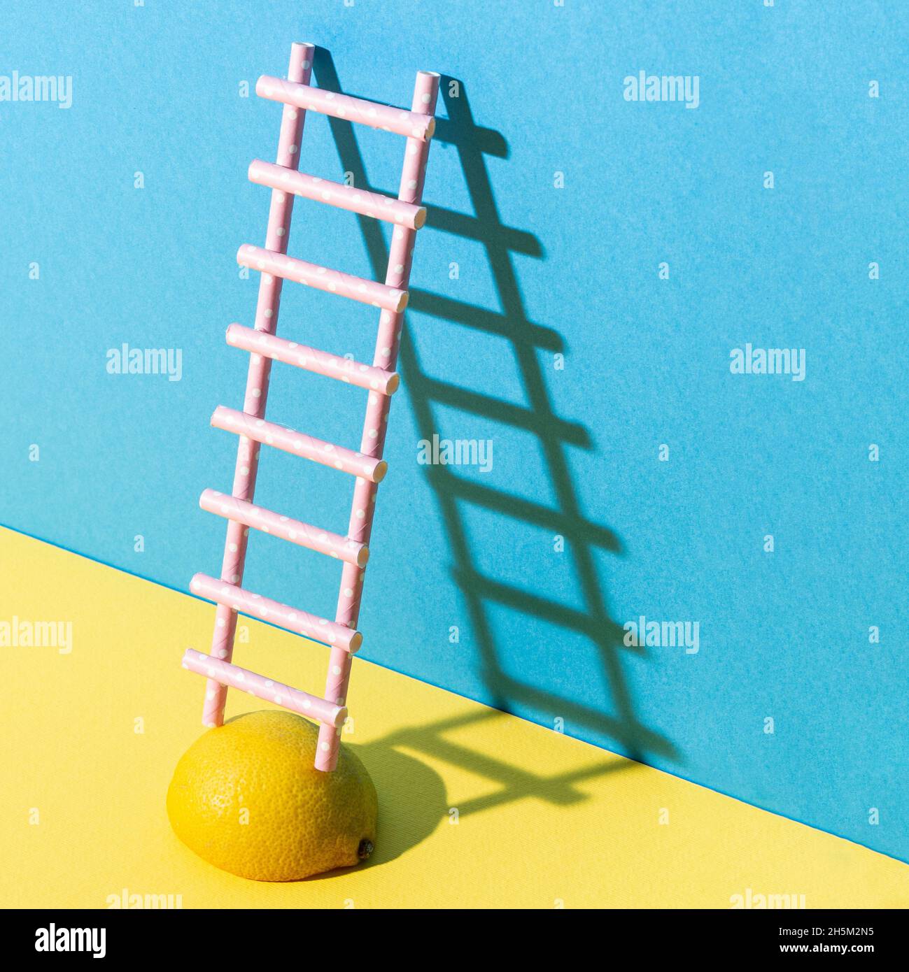 Ladder on lemon on a yellow and blue pastel background Stock Photo - Alamy